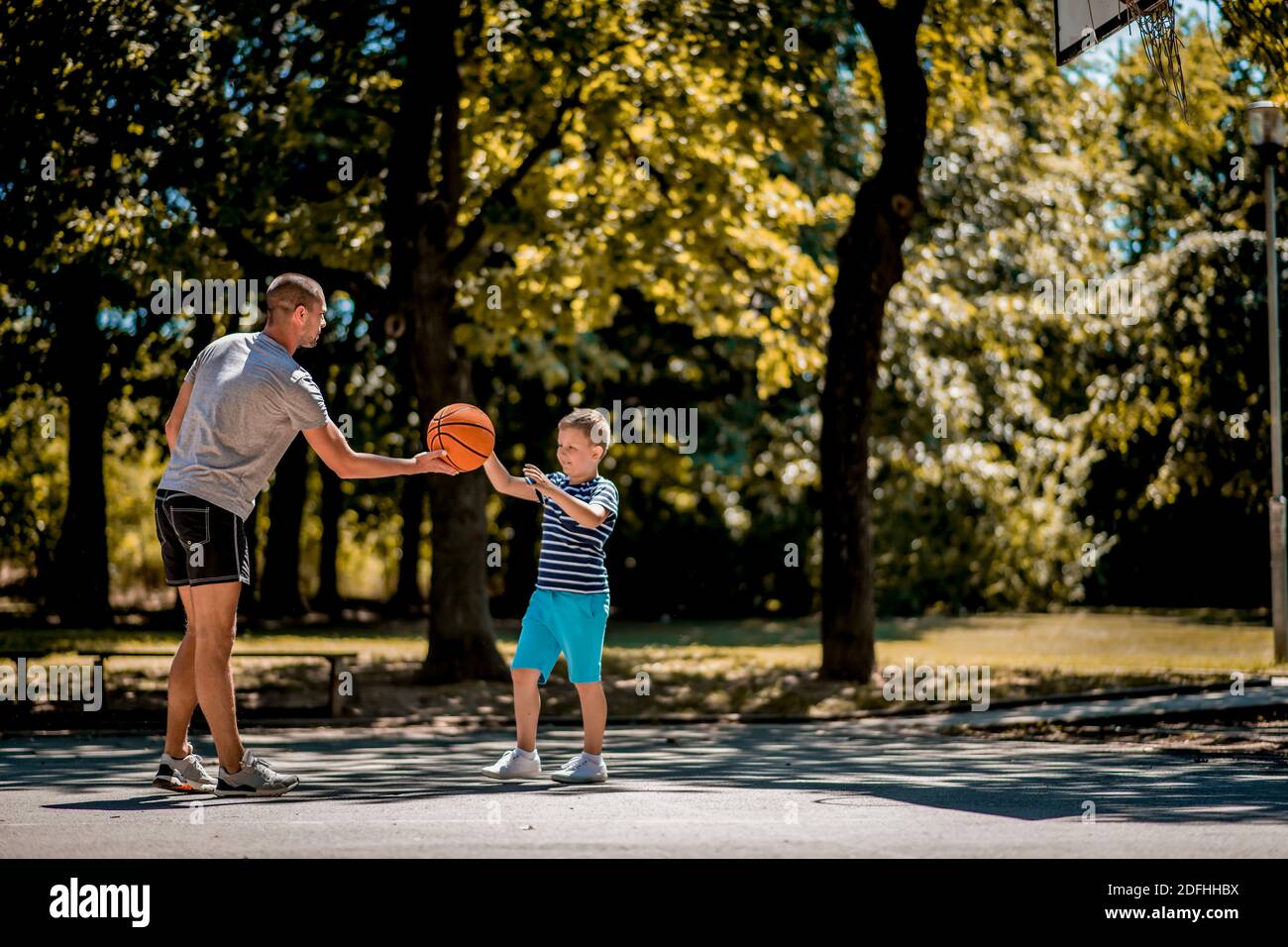 Cute blond boy practicing basketball with his coach Stock Photo - Alamy