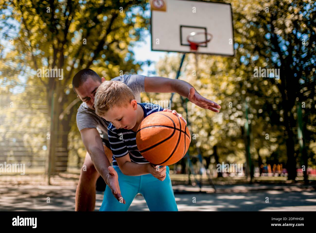 Cute blond boy practicing basketball with his coach Stock Photo - Alamy