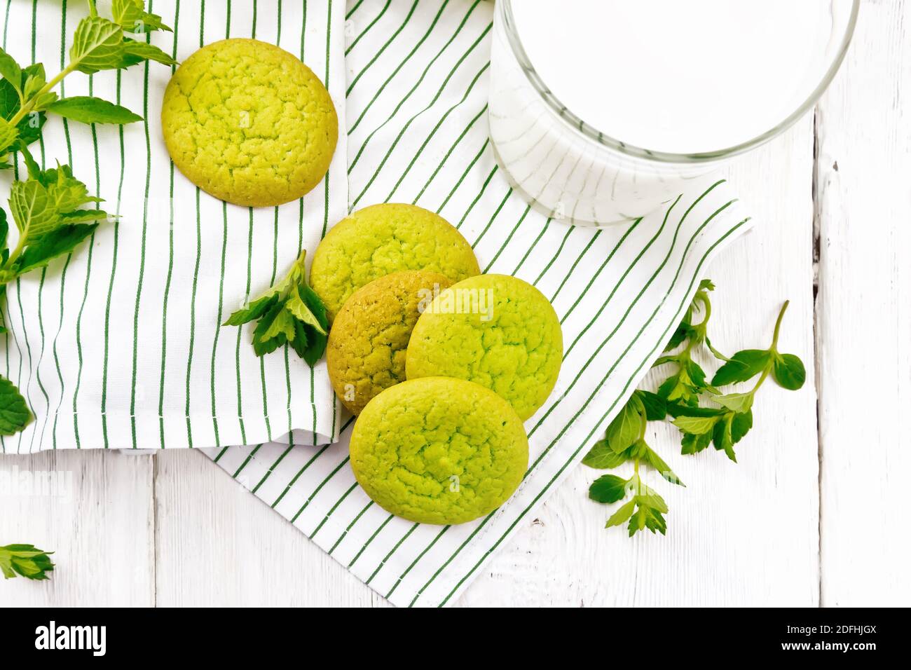 Green mint cookies on a towel with milk in a glass on wooden board ...