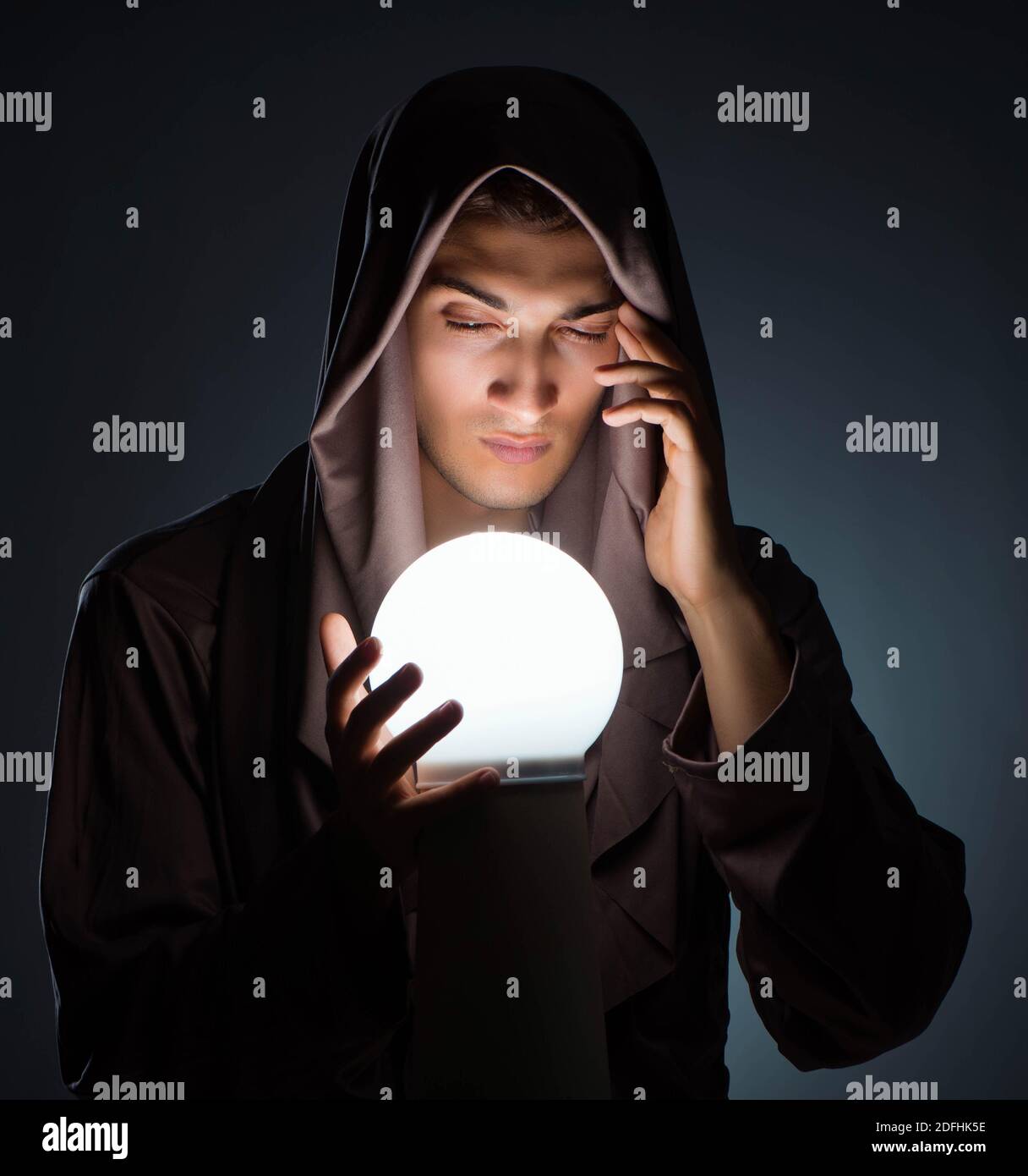 The young wizard with crystal ball in dark room Stock Photo - Alamy