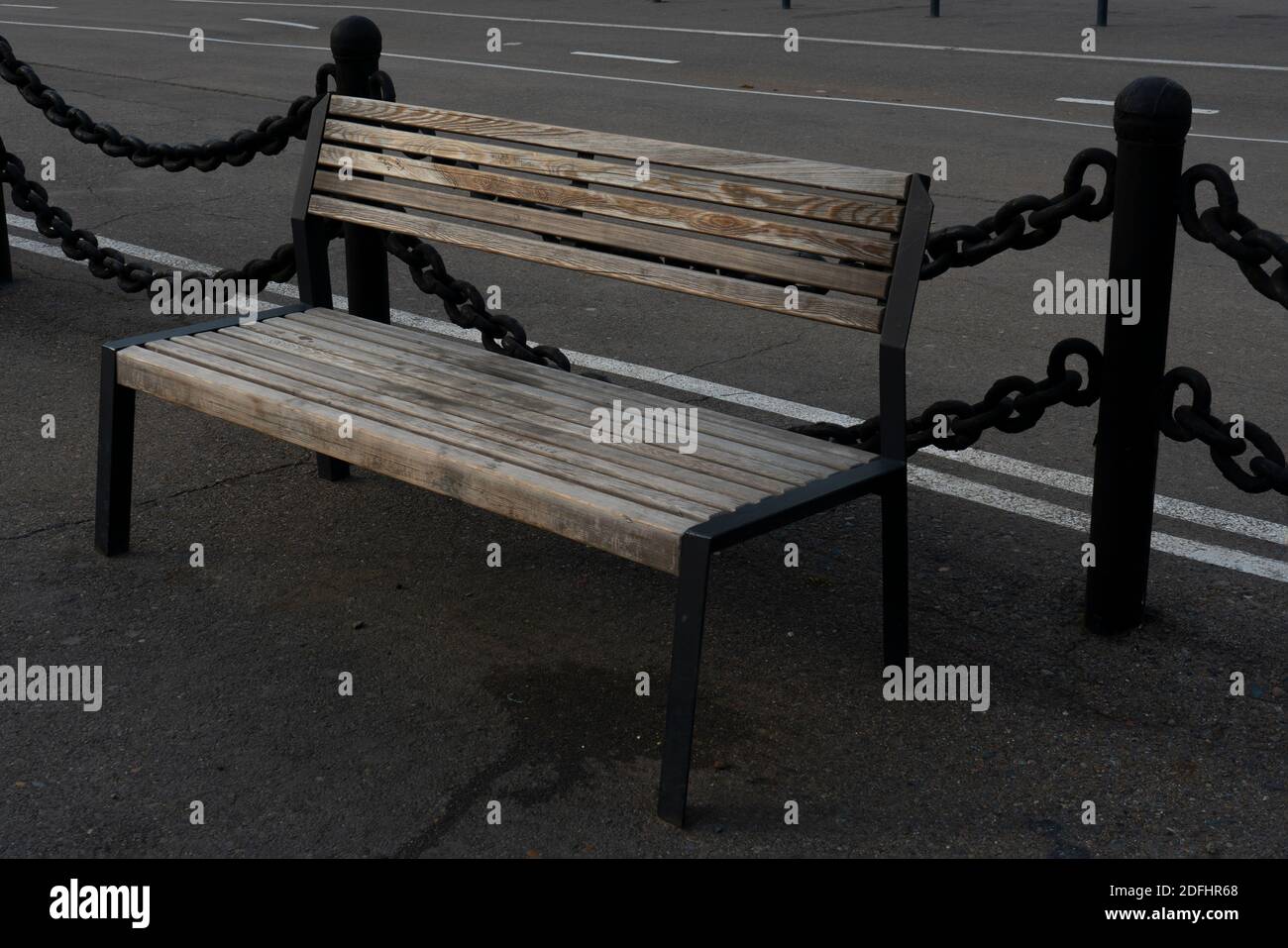 Wooden bench on the asphalt embankment fenced with pillars with massive ...