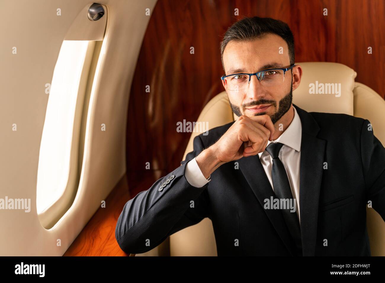Handsome businessman wearing elegant suit flying on exclusive private ...