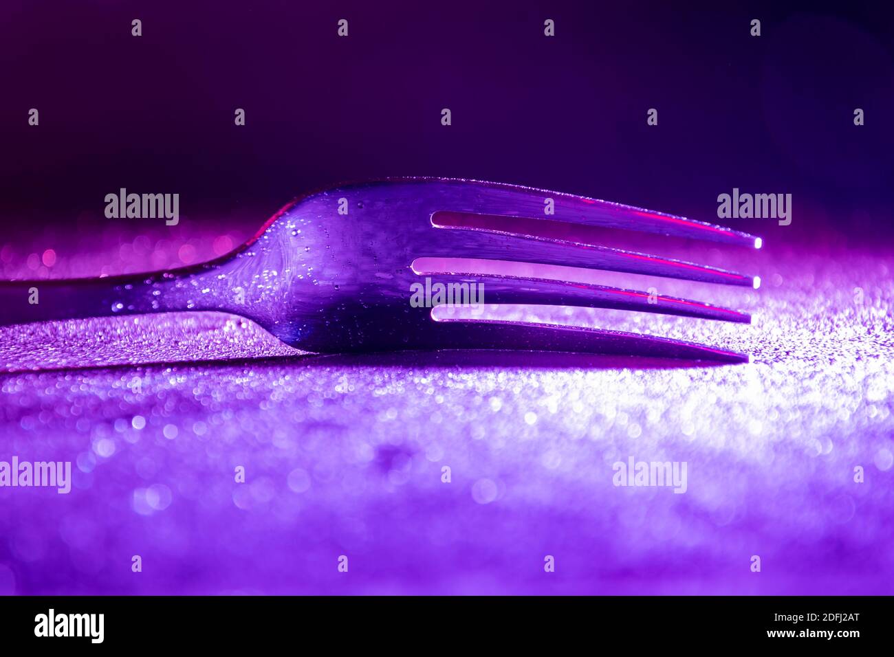 Single fork in the dark illuminated with colourful gradient LED light ...