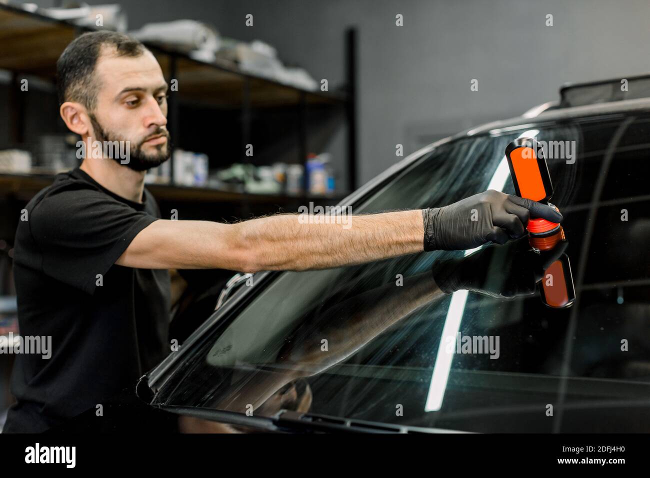 Handsome young male worker of auto detailing wash service, coating car ...