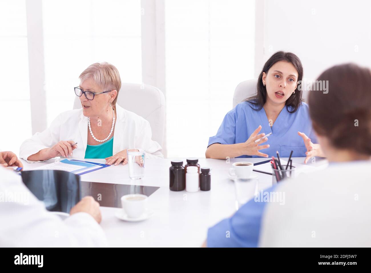 Medical team sitting and discussing about patient diagnosis in ...