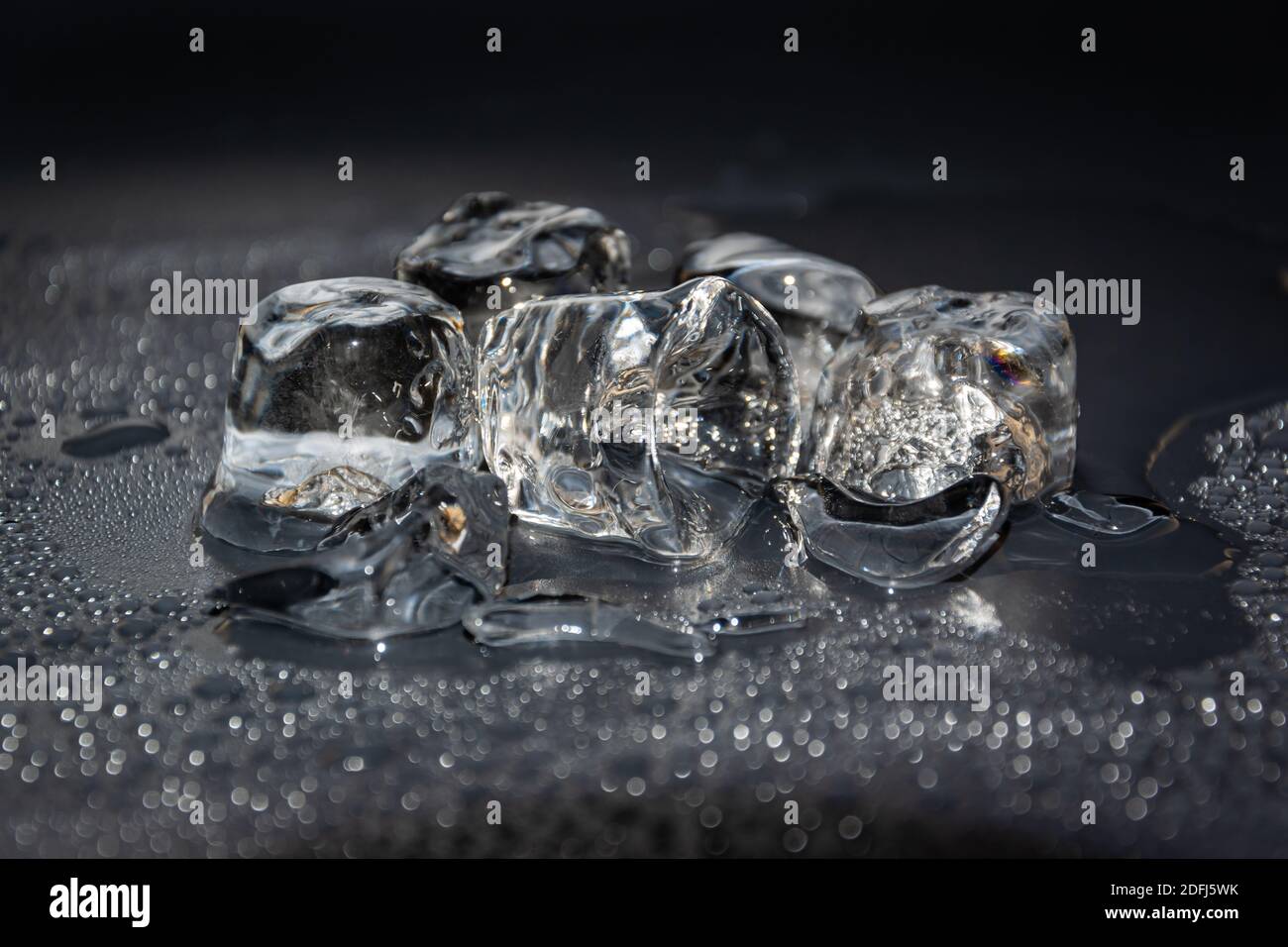 Melting frozen ice cubes illuminated with coloured LED light in the ...