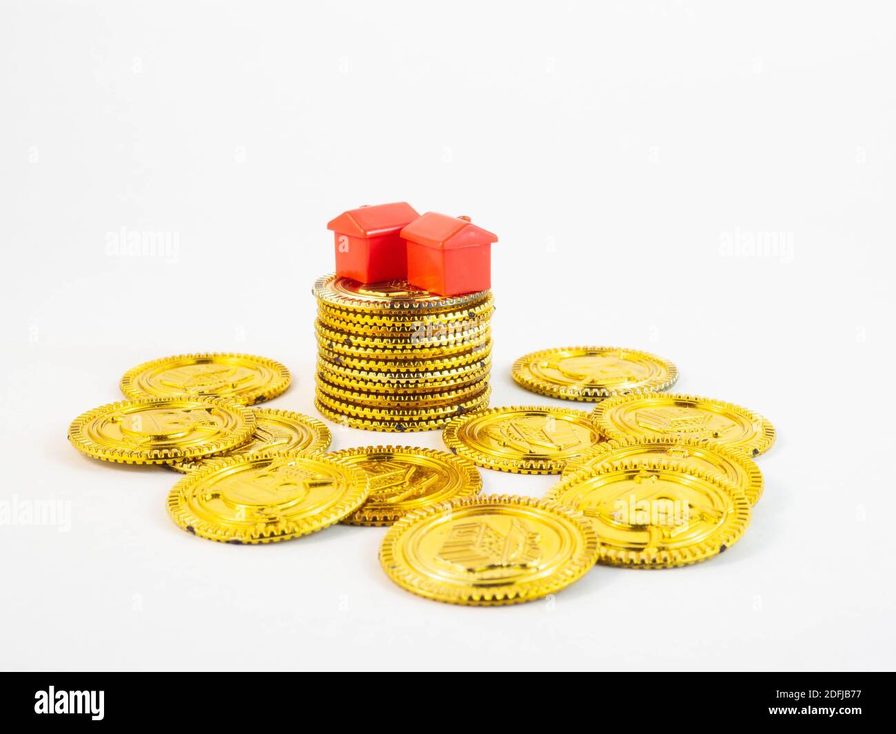 A set of small houses of red color surrounded by gold coins. Concept ...