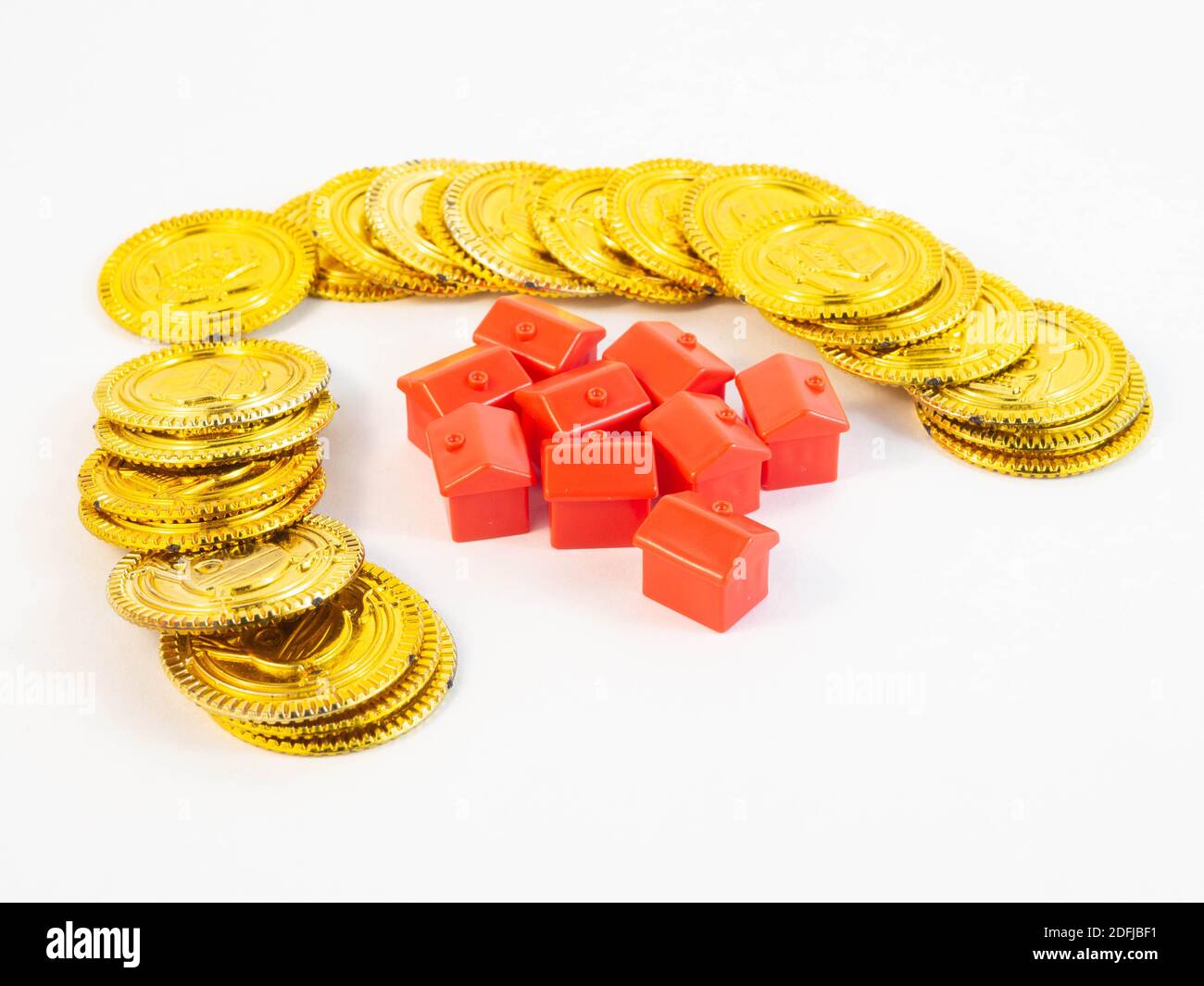 A set of small houses of red color surrounded by gold coins. Concept ...