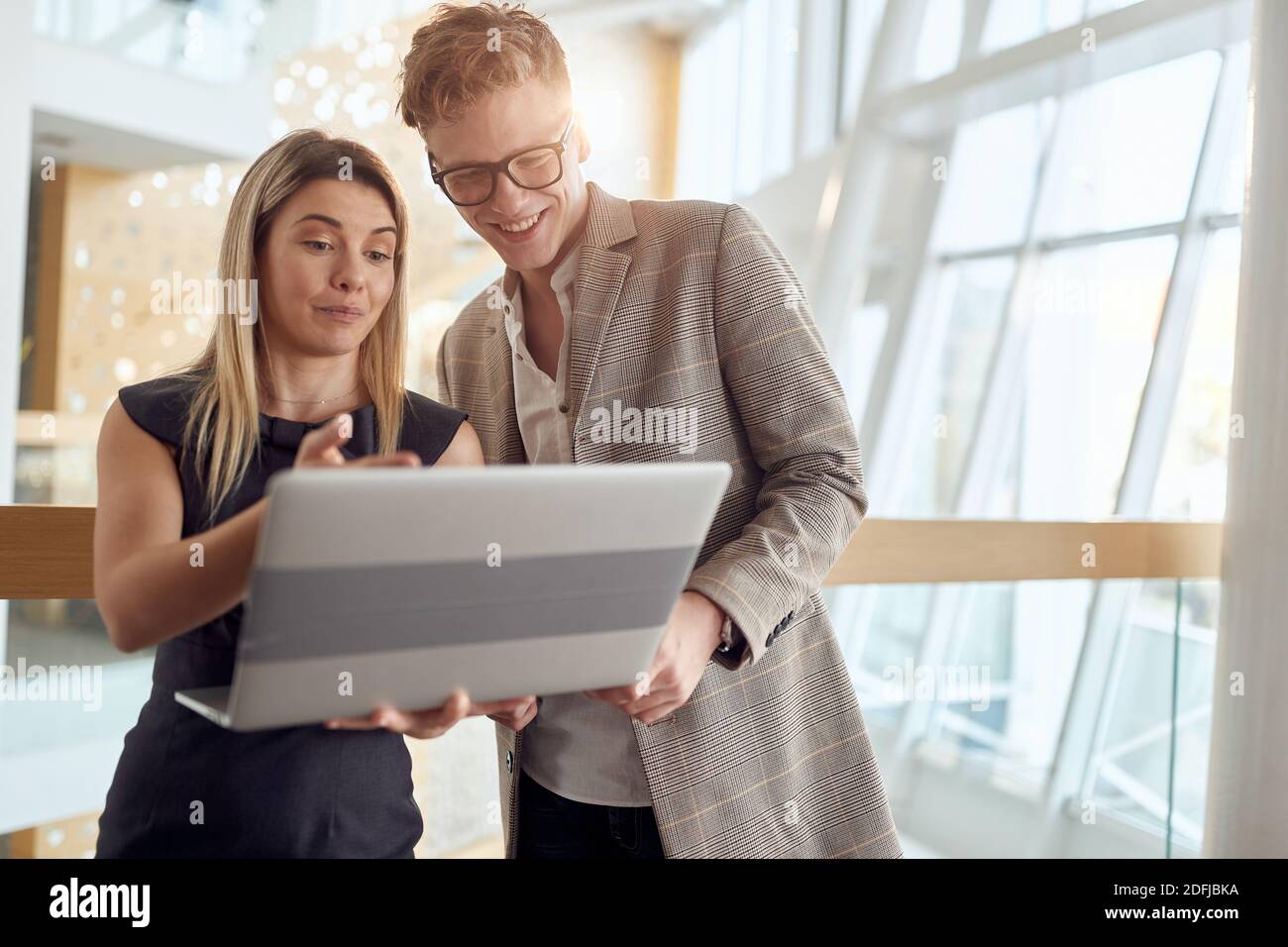 A female employee helping a young male colleague in pleasant atmosphere ...