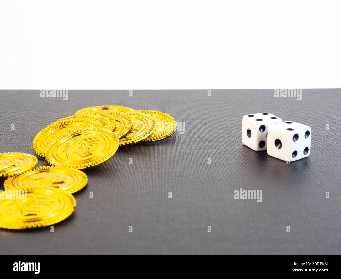 A pile of gold coins, with a set of three red houses and two white dice ...