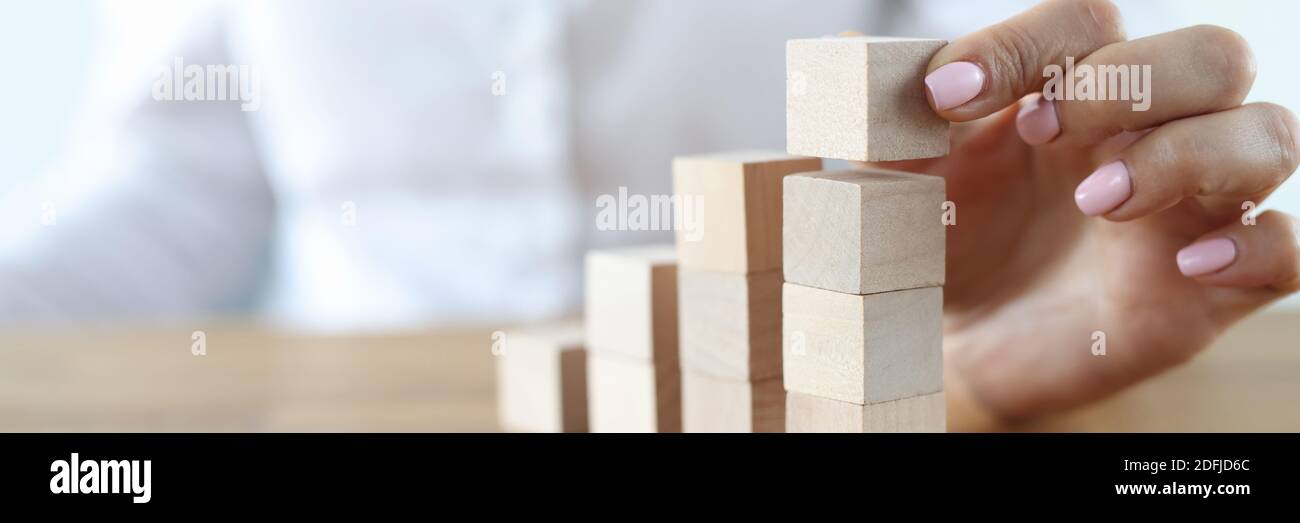 Woman build tower from wooden cubes on table close-up Stock Photo - Alamy