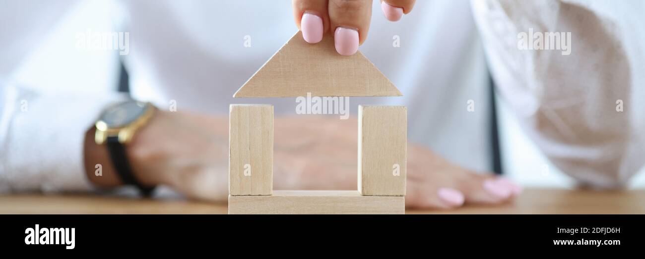 Woman build house from wooden cubes on table Stock Photo - Alamy