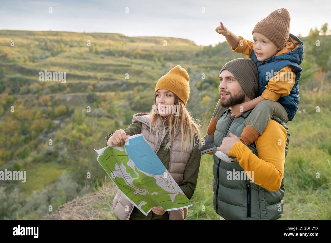 Happy young family of backpackers with map looking forwards while ...