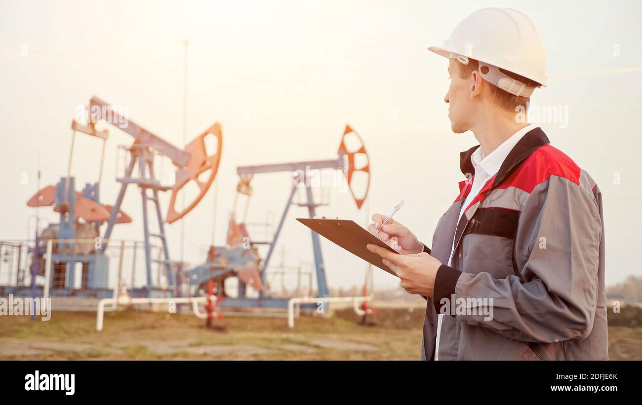 engineer writing on clipboard in oil field. Industrial, oil and gas ...
