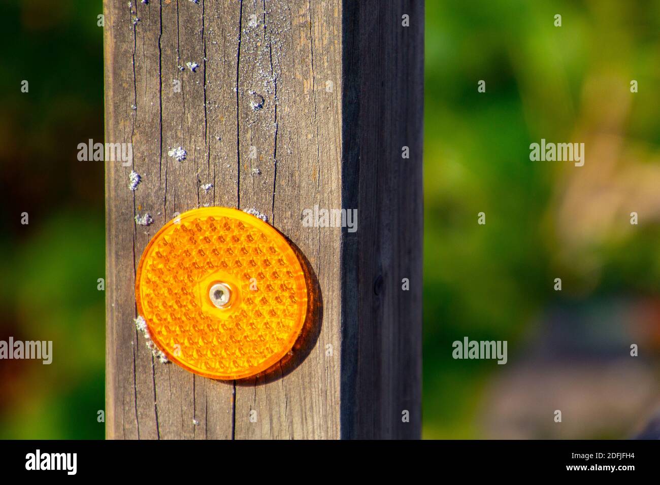 Round bright orange plastic reflector on a wooden post Stock Photo - Alamy