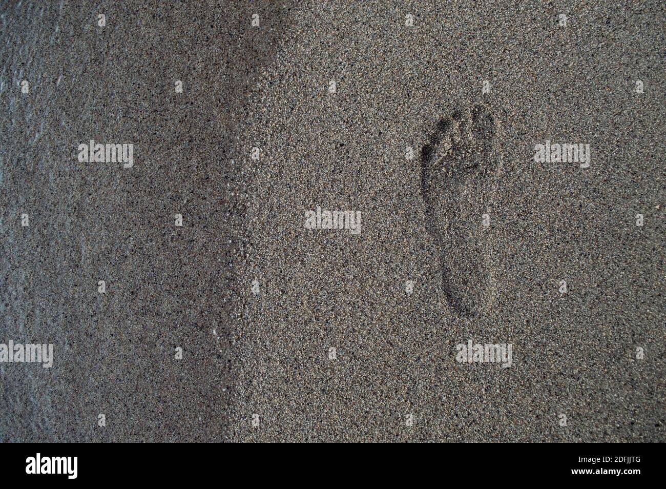 A footprint in the sand with receding water on the ocean shore Stock ...