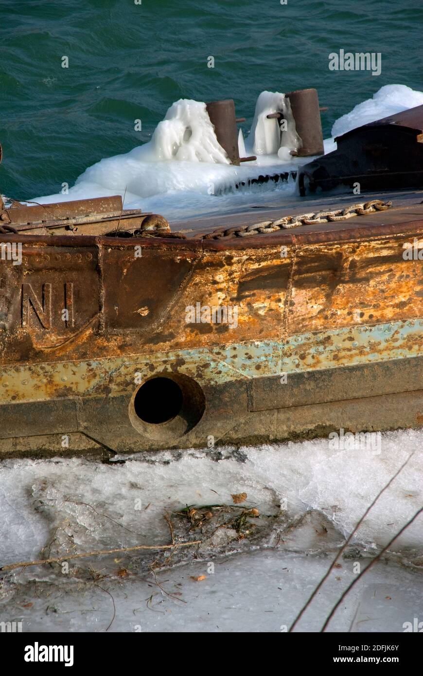 The wreck of a small barge caught in ice on the banks of the river ...