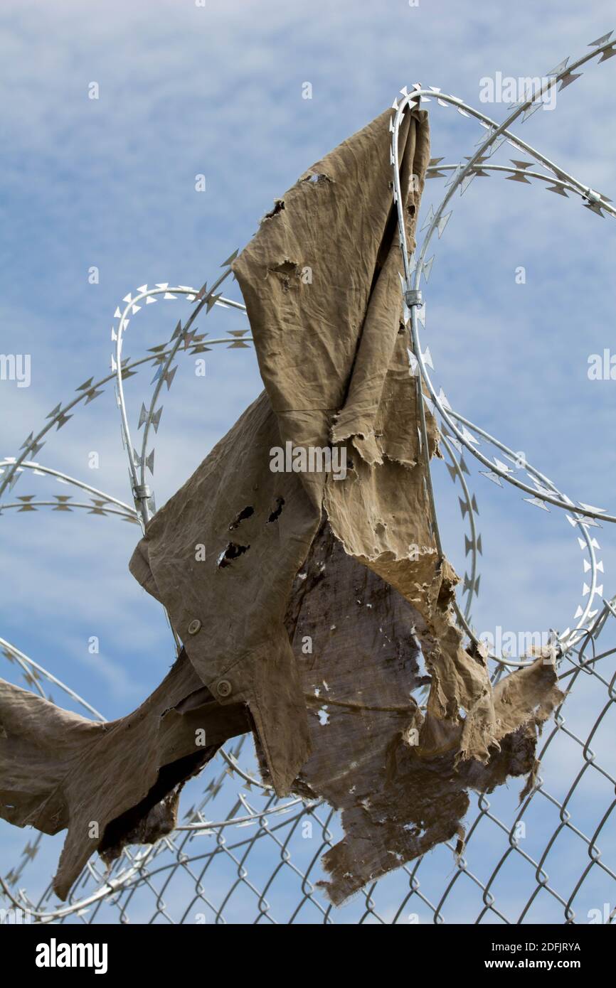 Torn material or coat on razor wire, suggestive of a failed escape from ...