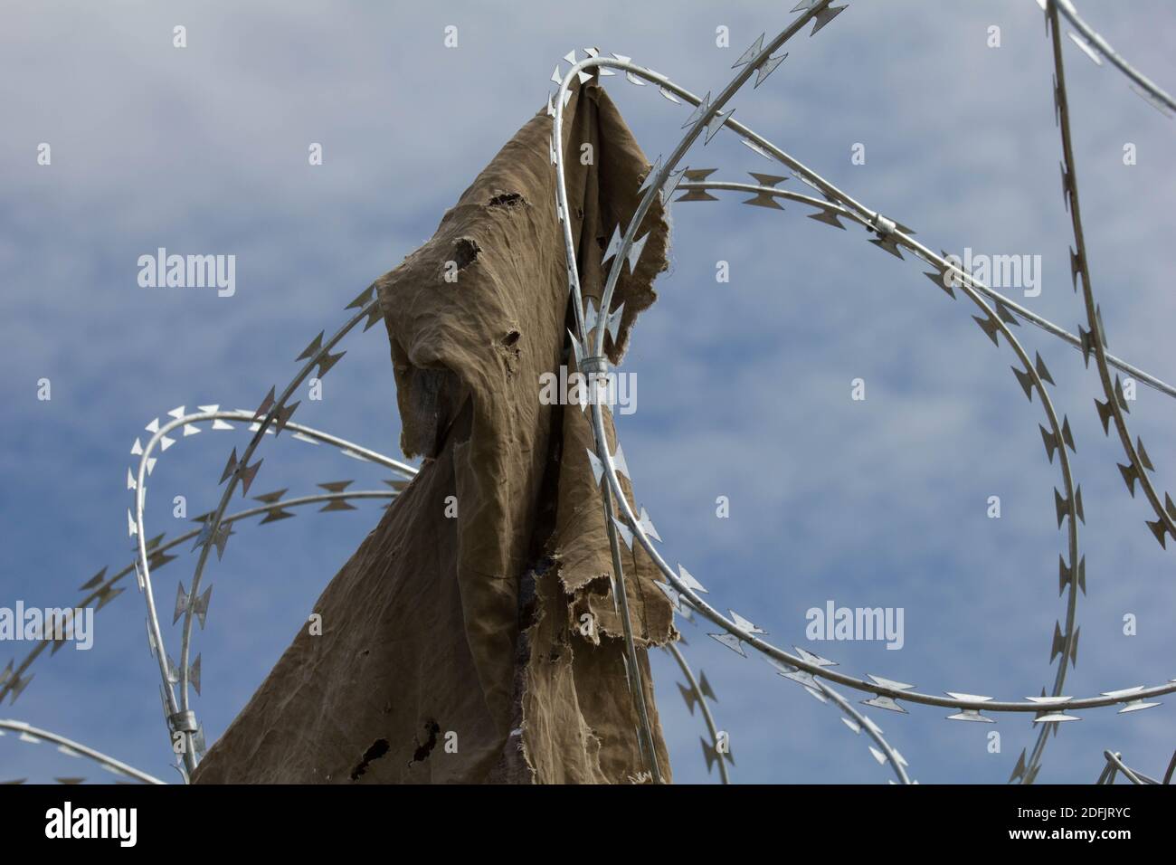 Torn material or coat on razor wire, suggestive of a failed escape from ...