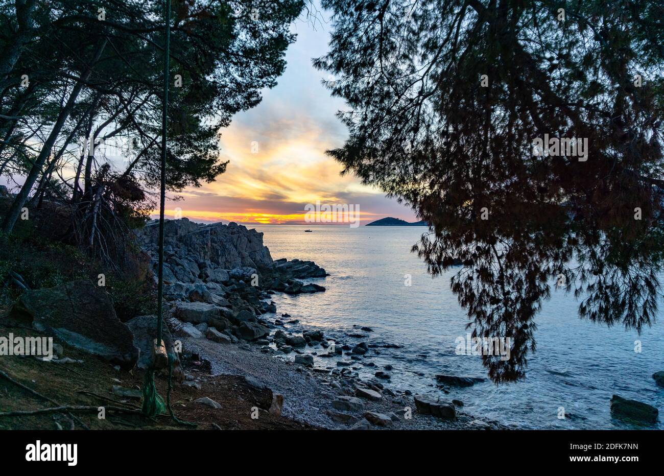 Primitive swing at cliff beach under trees at colourful sunset Stock ...