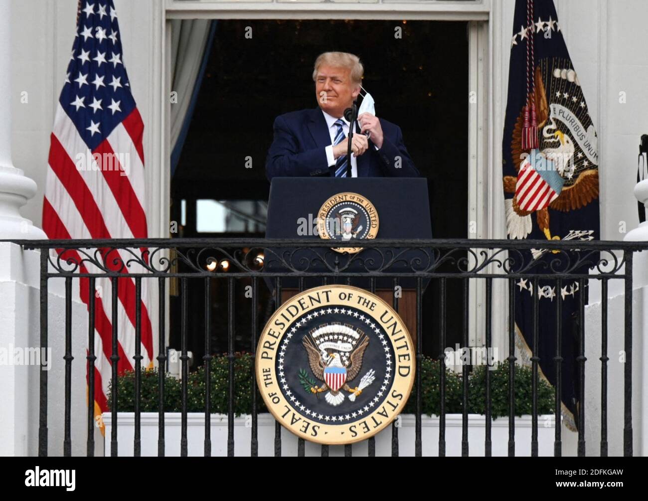U.S. President Donald Trump removes a protective mask ahead of speaking ...