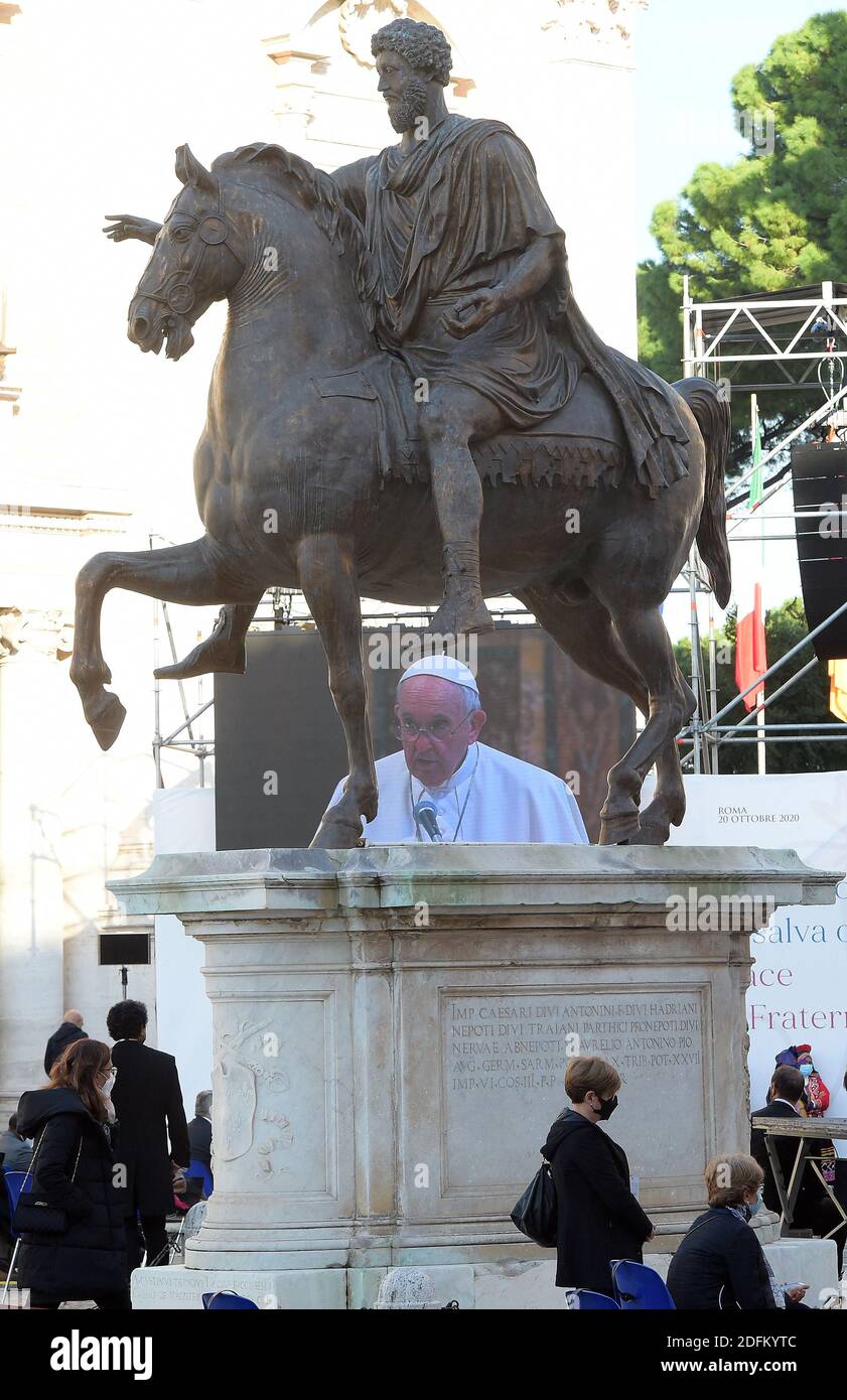 Pope Francis is seen on a TV screen behind the statue of Roman Emperor ...