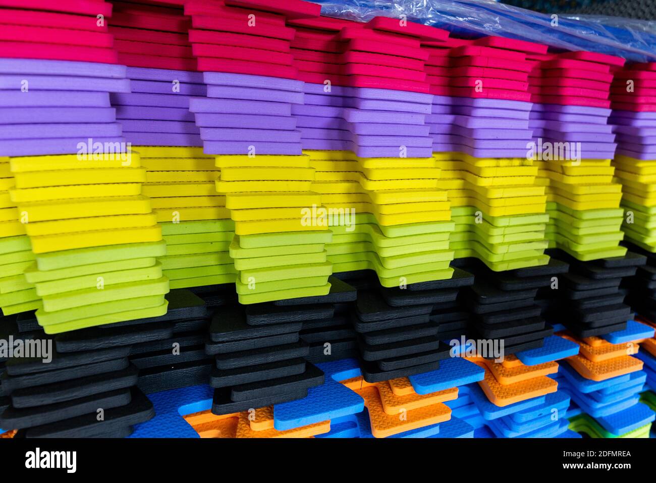 A closeup of colorful stacked play mats for the floor on the shelves ...