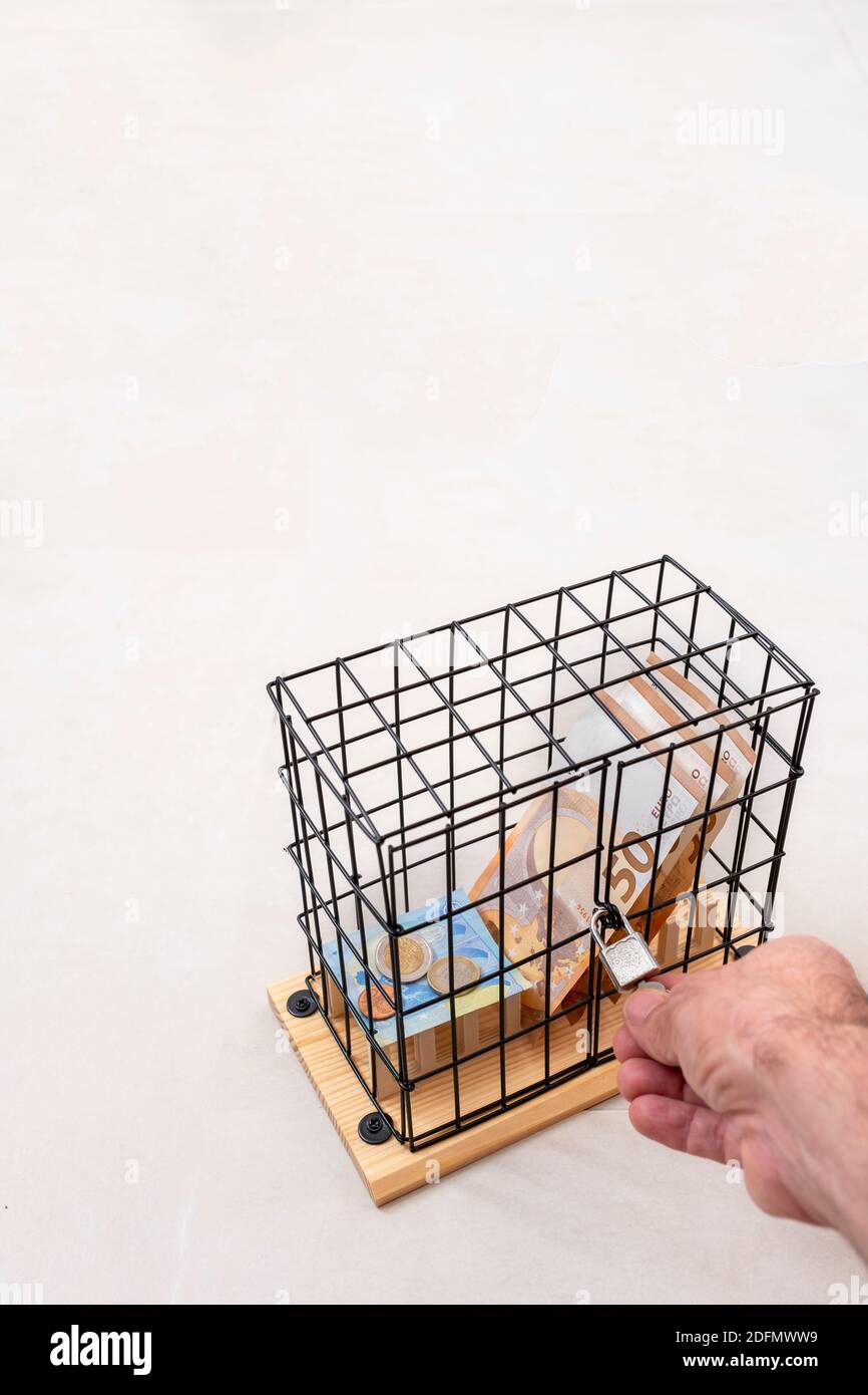 hand with a small key opening or closing a small cage with a lock with ...
