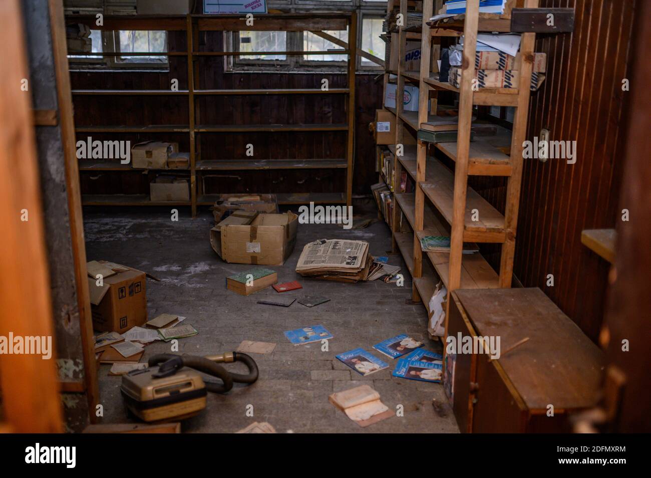 An old abandoned, dusty room with wooden shelves and scattered books ...