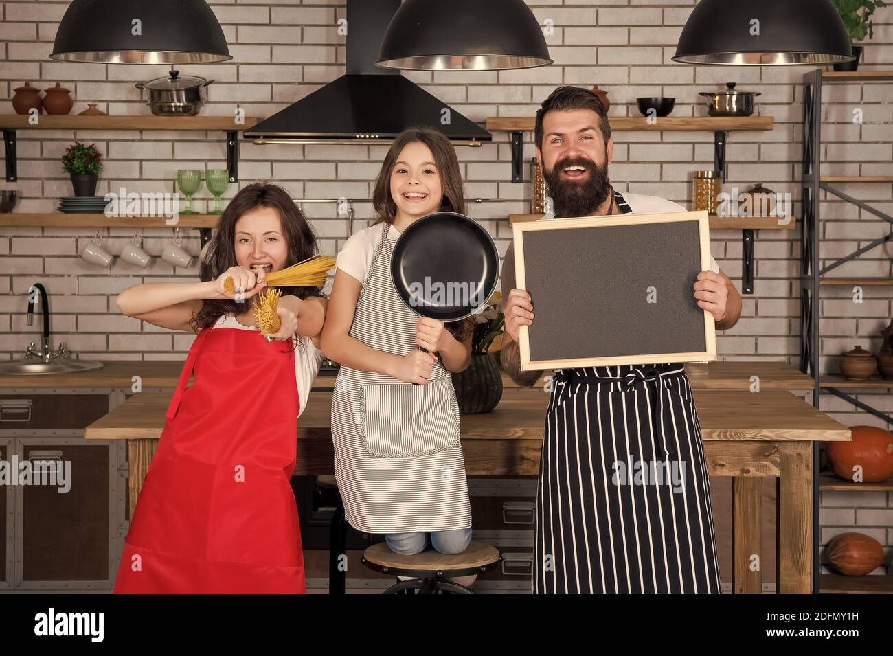 Best cooking team. Mom dad and daughter aprons in kitchen. Lunch time ...