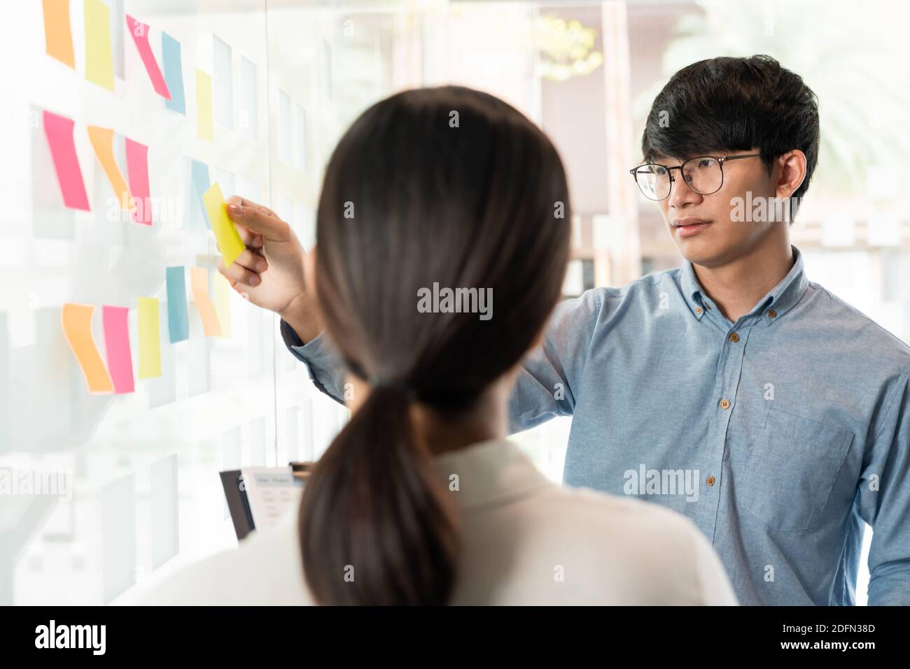 Business manager showing idea for her team and stick many memo paper on ...
