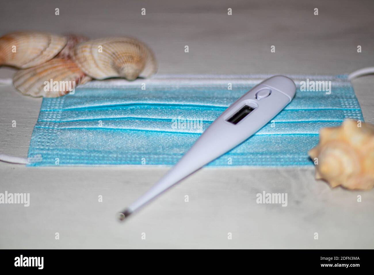 Blue protective medical mask with thermometer and seashells Stock Photo ...