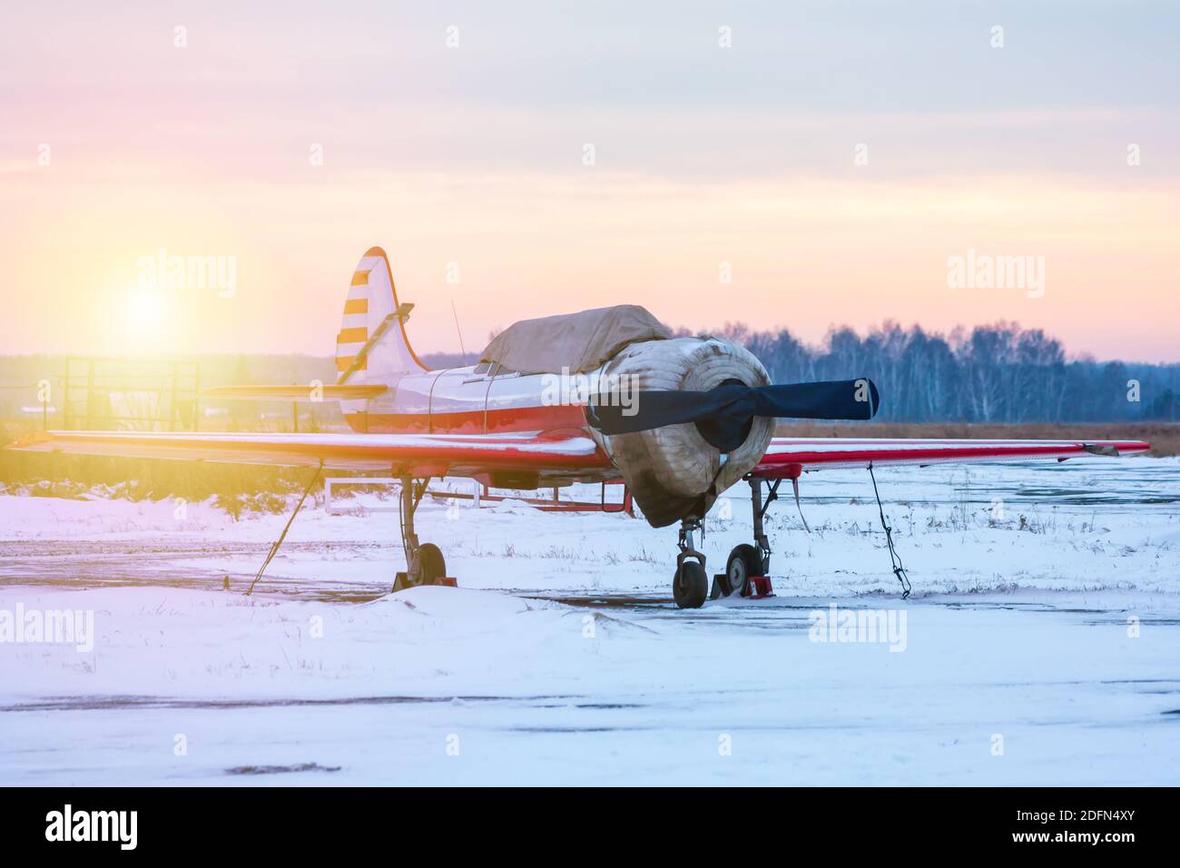 Small sports airplane on the apron of a snowy airfield in cold winter ...