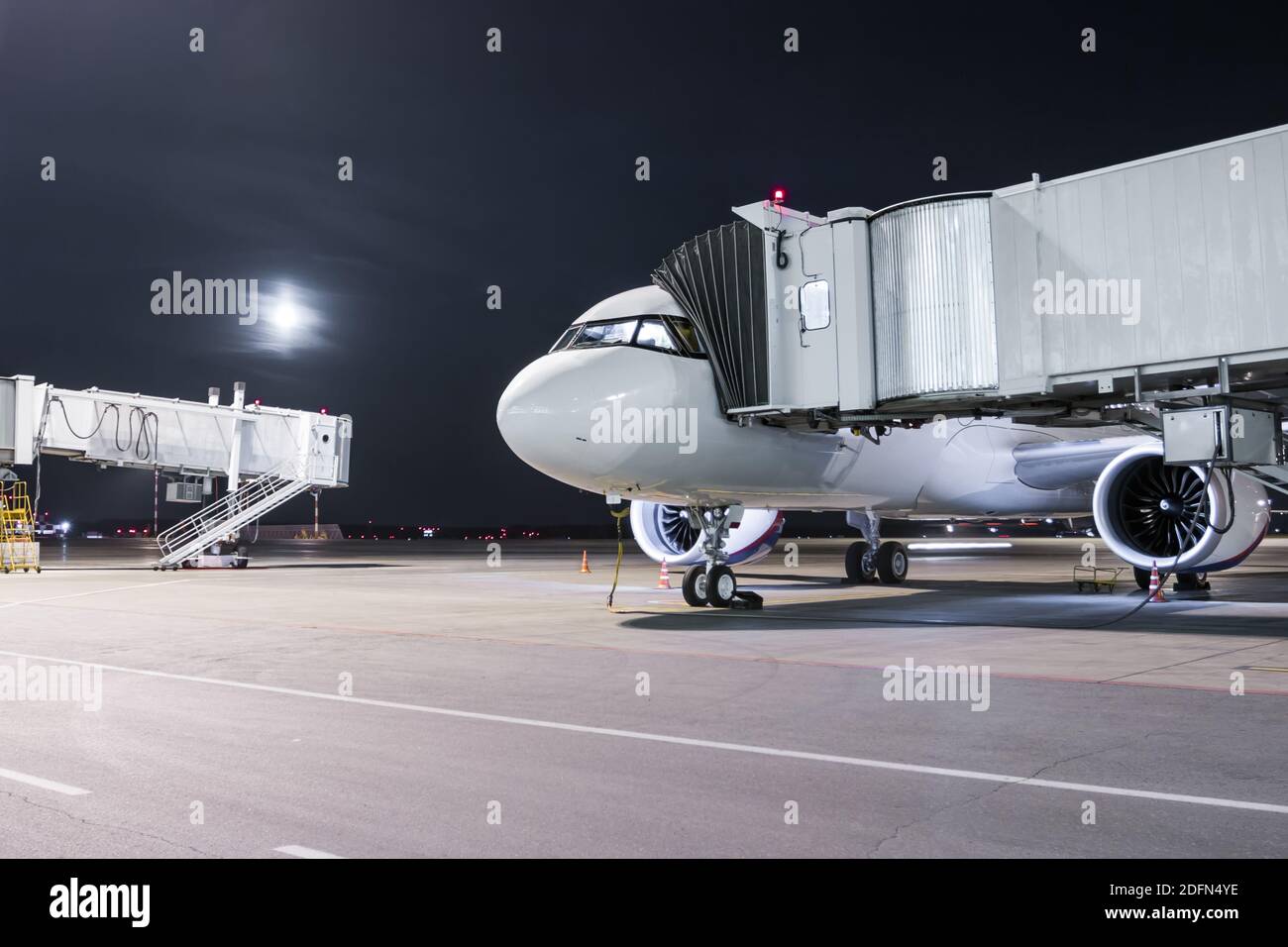 A white passenger jet plane stands at the air bridge connected to an ...