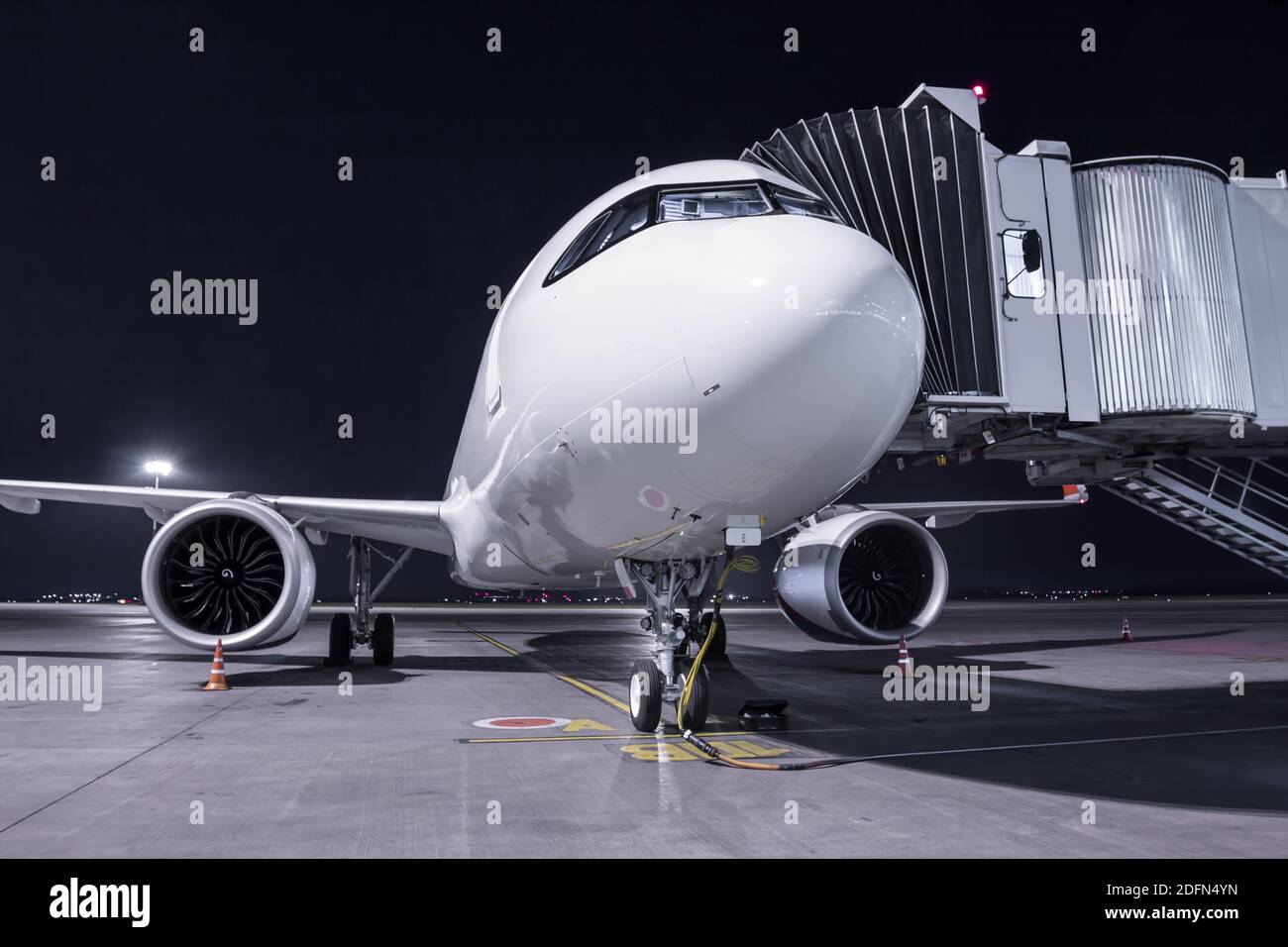 A white passenger airplane stands at the jetway connected to an ...