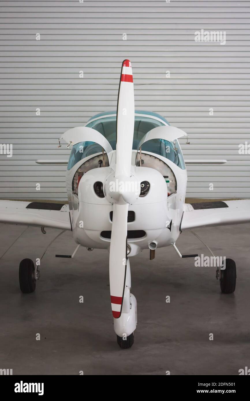 Close front view of a small white sports plane in a hangar. The ...
