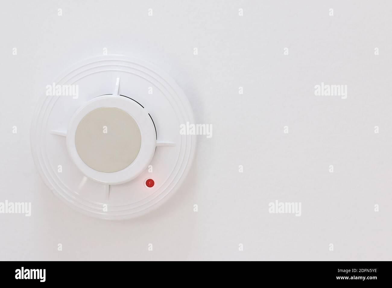 A smoke detector hangs on the white ceiling. Fire prevention device in ...