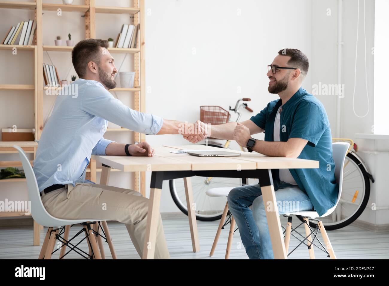 Smiling male employees handshake at meeting in office Stock Photo - Alamy
