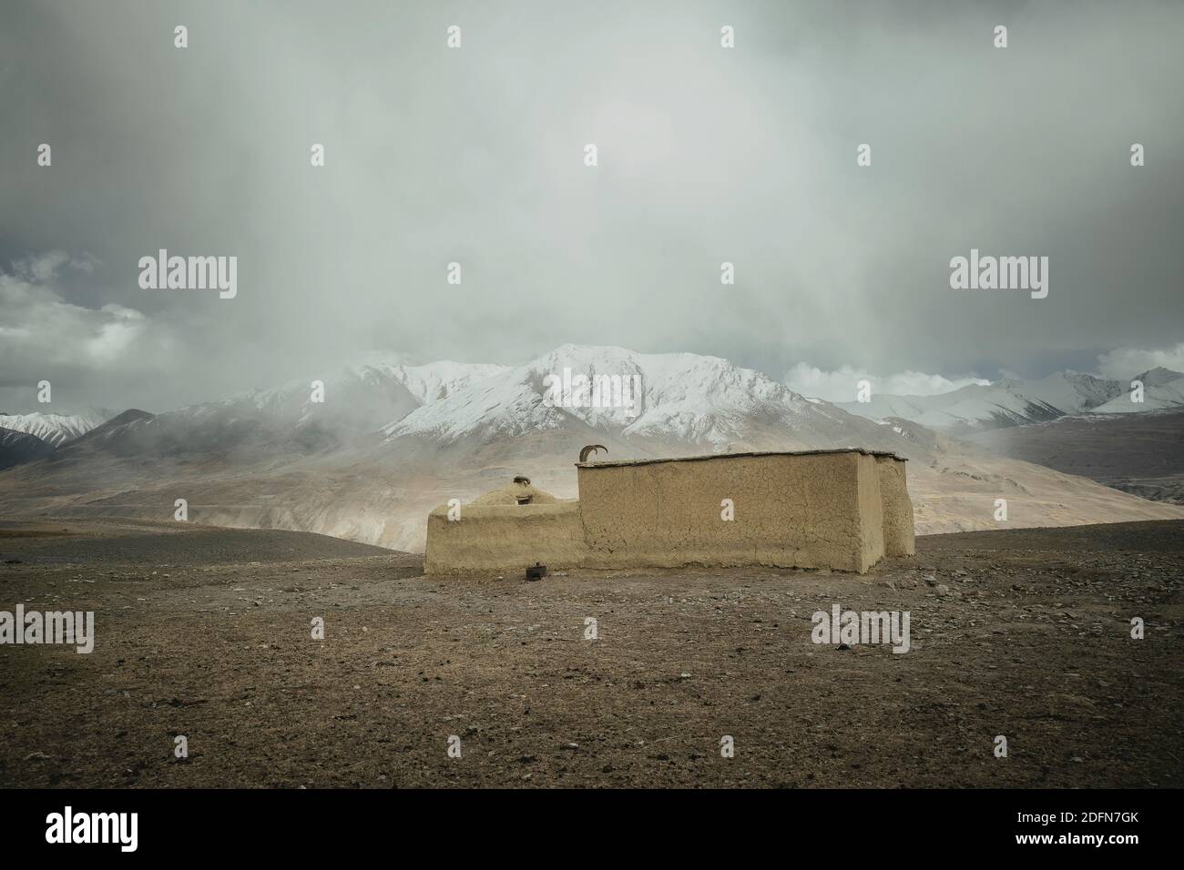 Clay mosque decorated with the horns of an ibex, behind it the snow ...