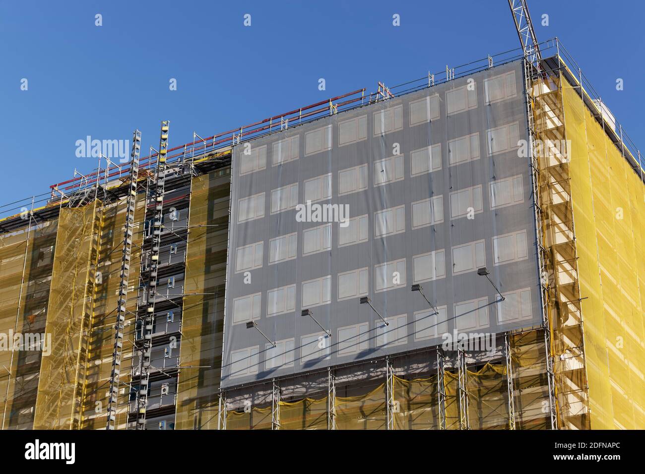 Facade with scaffolding and yellow cladding, building refurbishment ...