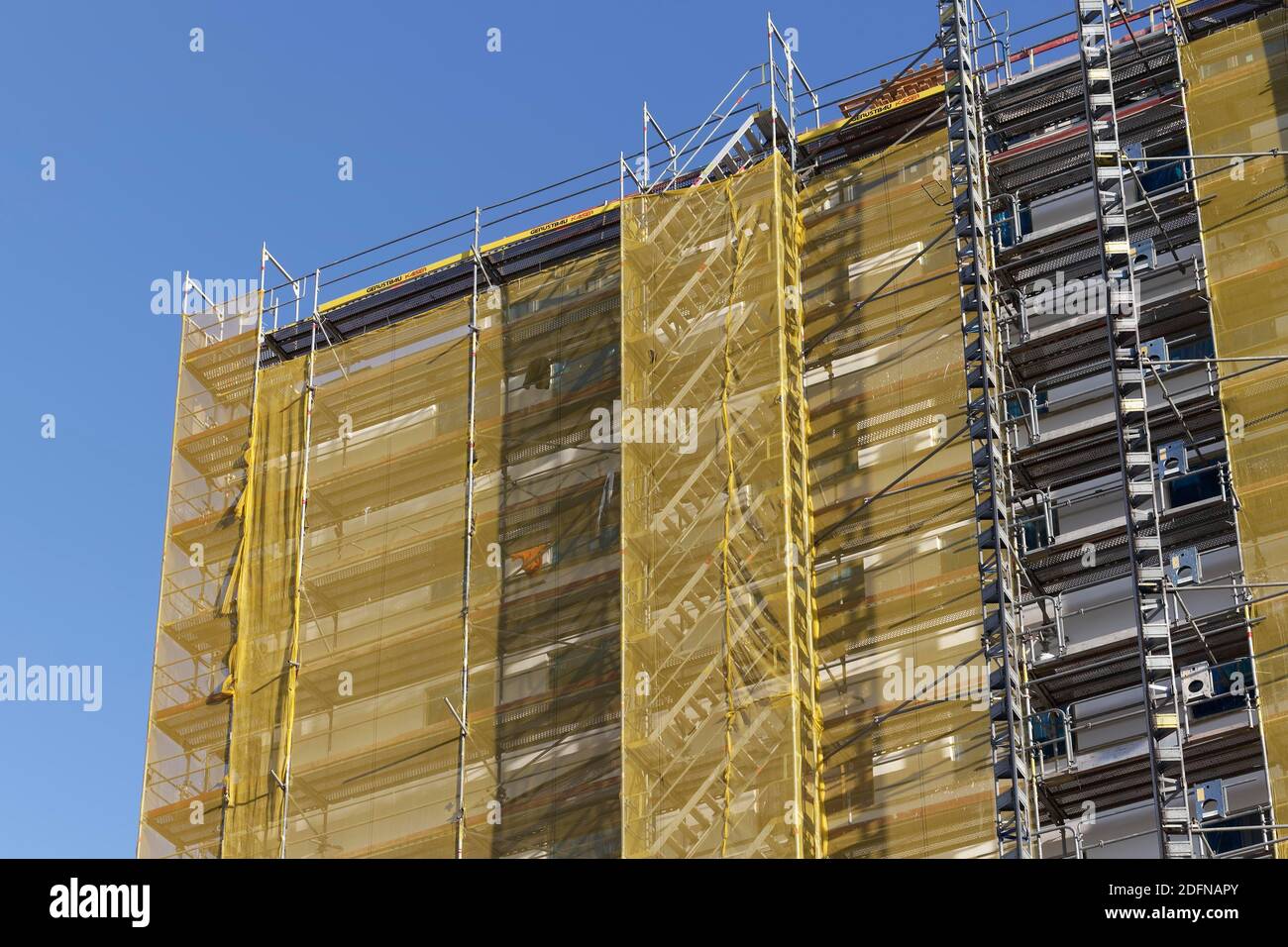 Facade with scaffolding and yellow cladding, building refurbishment ...