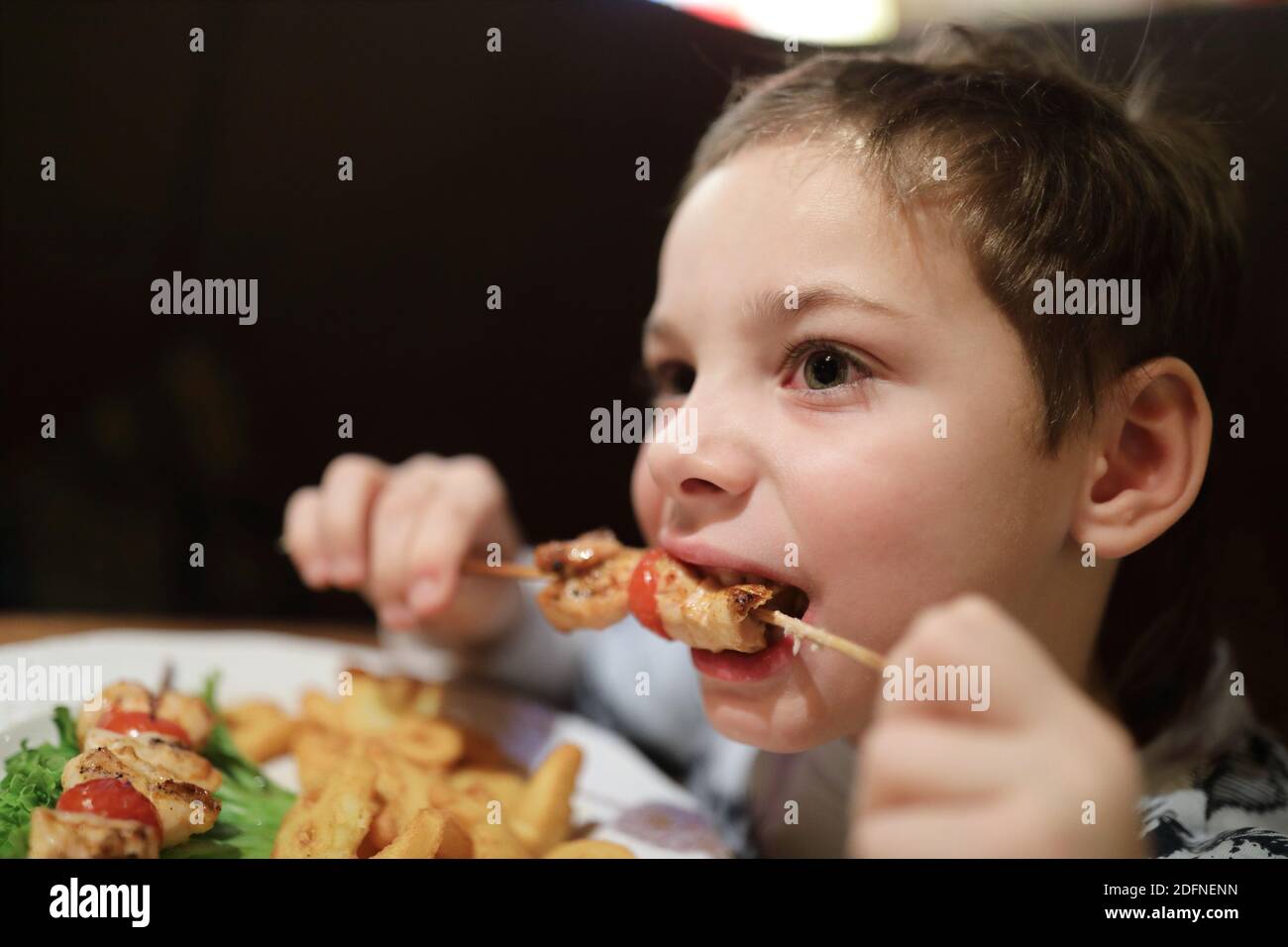 Child eating kebab on skewer in restaurant Stock Photo - Alamy