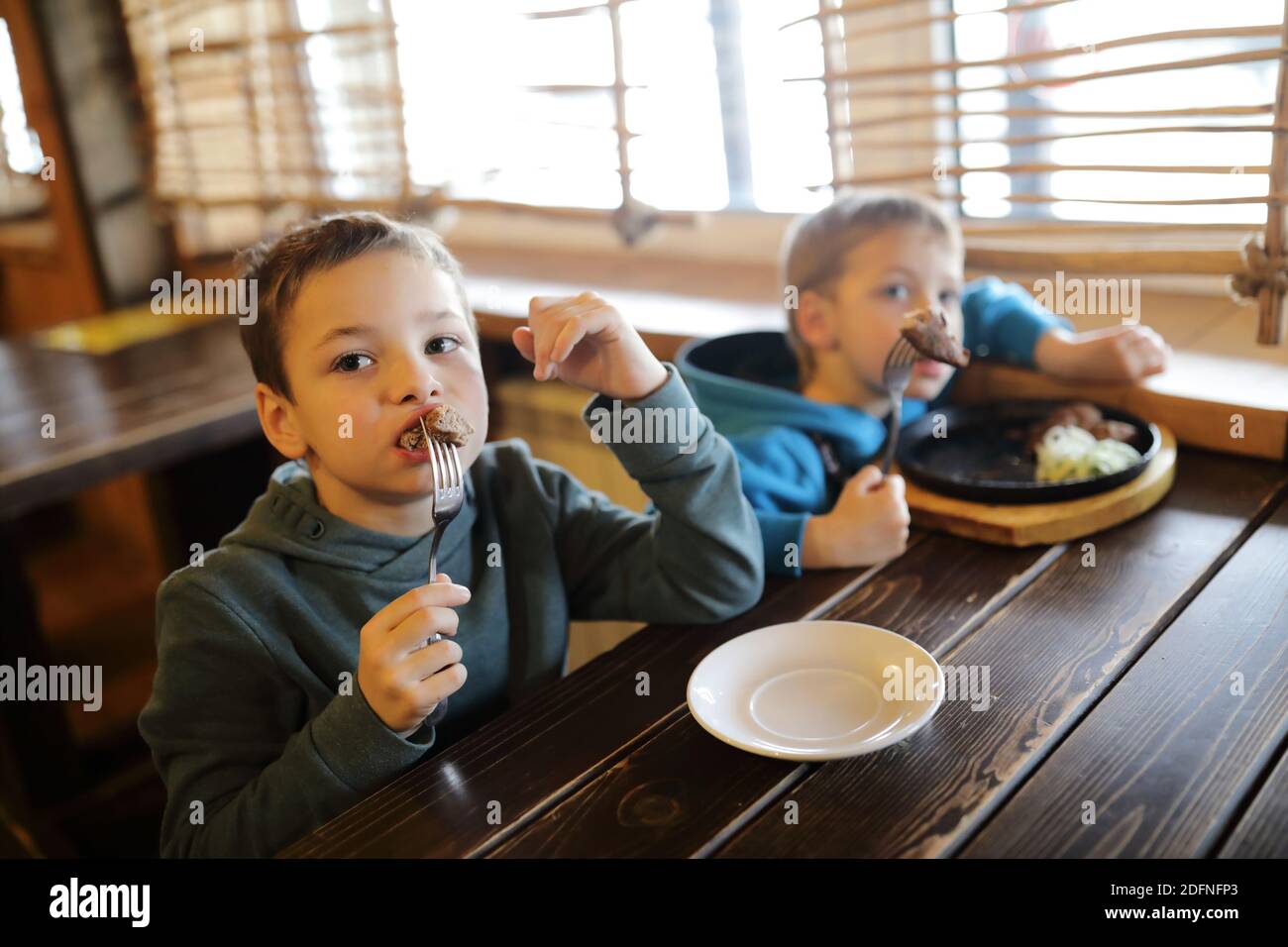 Two kids have lunch in a cafe Stock Photo - Alamy