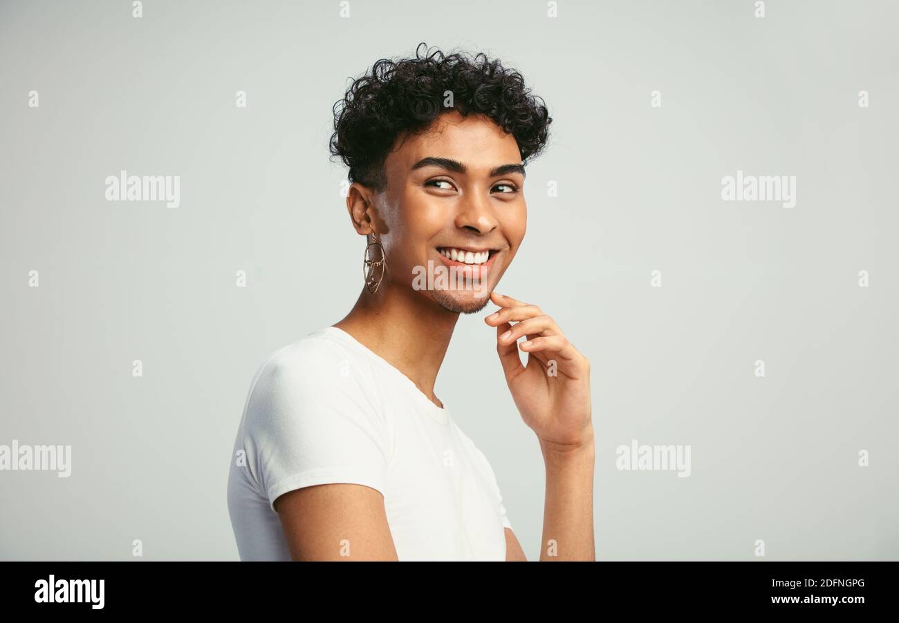 Smiling androgynous man with earring. Man looking away and smiling ...