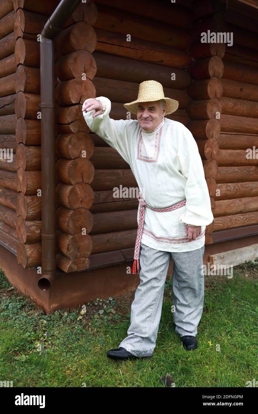 Elderly man in traditional Belarusian clothes on background of log ...