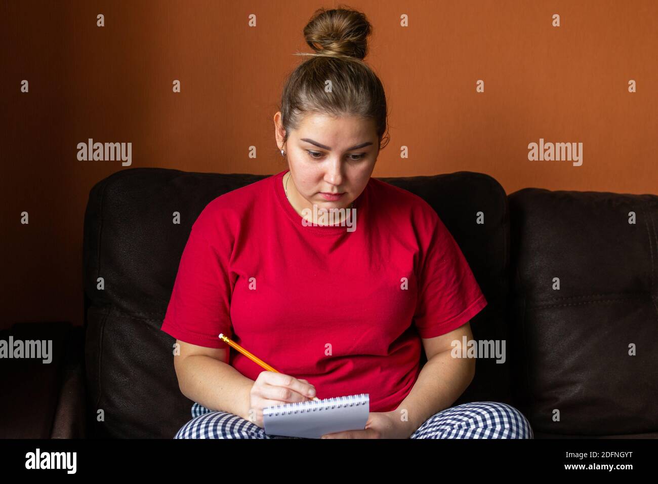 Beautiful young woman makes notes with a pencil in a notebook Stock ...