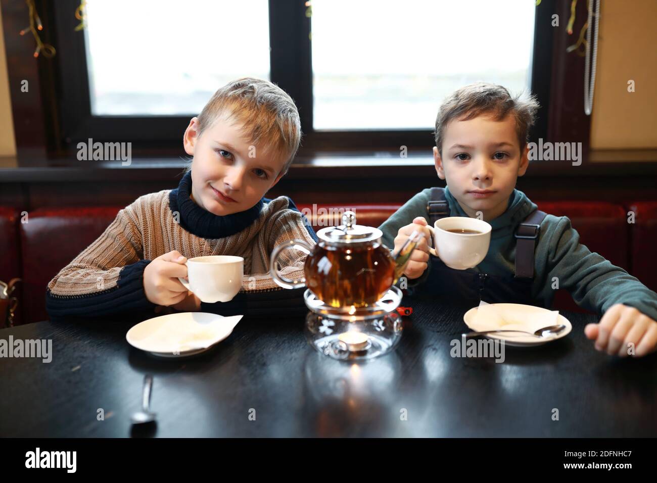Two boys drink tea at table in cafe Stock Photo - Alamy