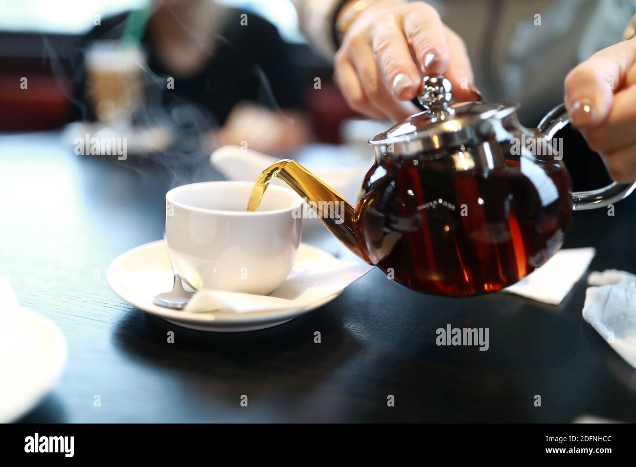 Waiter pouring tea into cup in cafe Stock Photo - Alamy