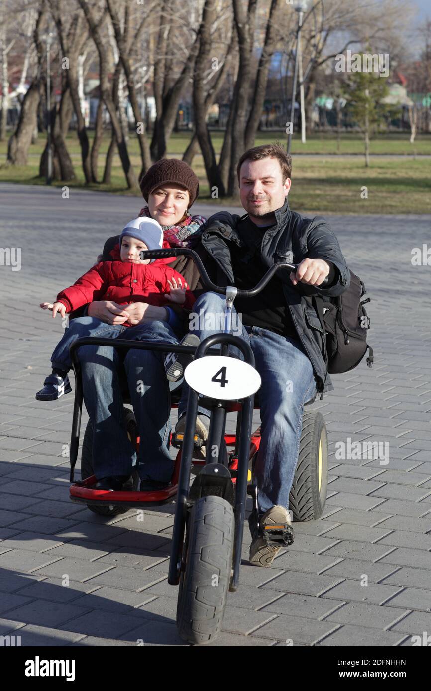 Family riding a three wheeled bicycle at park in spring Stock Photo - Alamy