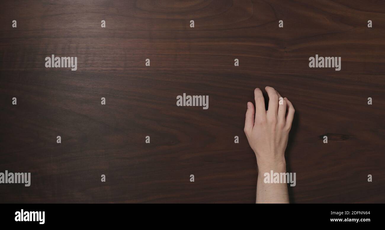 Top view man hand finger tap on black walnut table with copy space ...